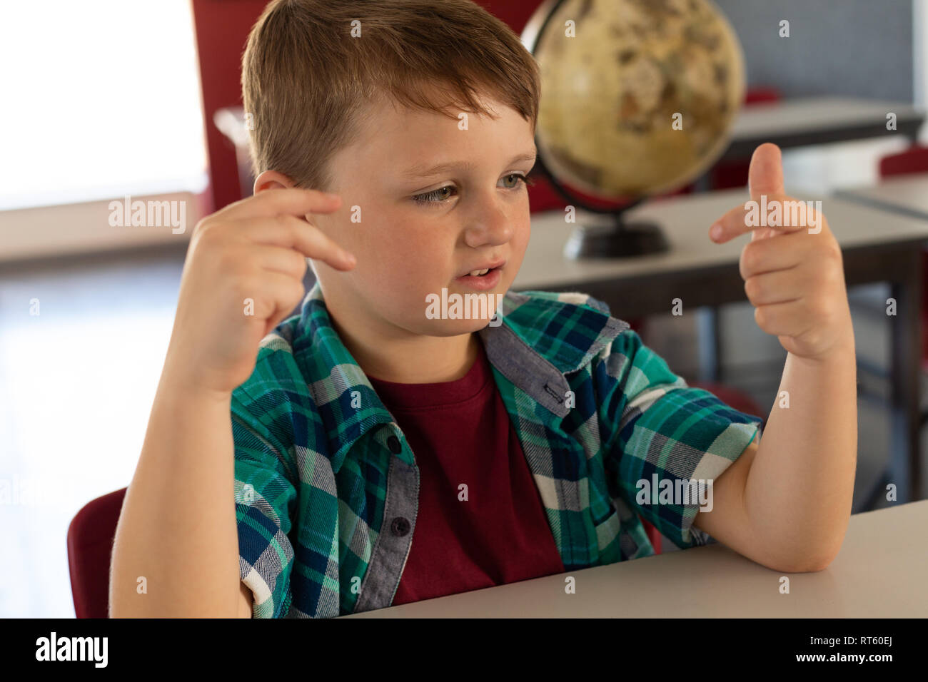 Boy counting with his finger at desk in a classroom Stock Photo - Alamy