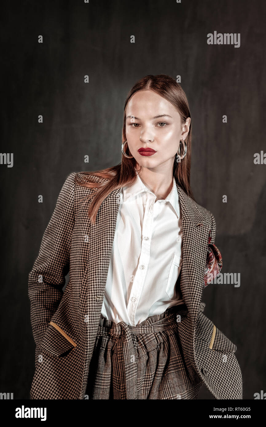 So serious. Delighted model standing over grey background and ...