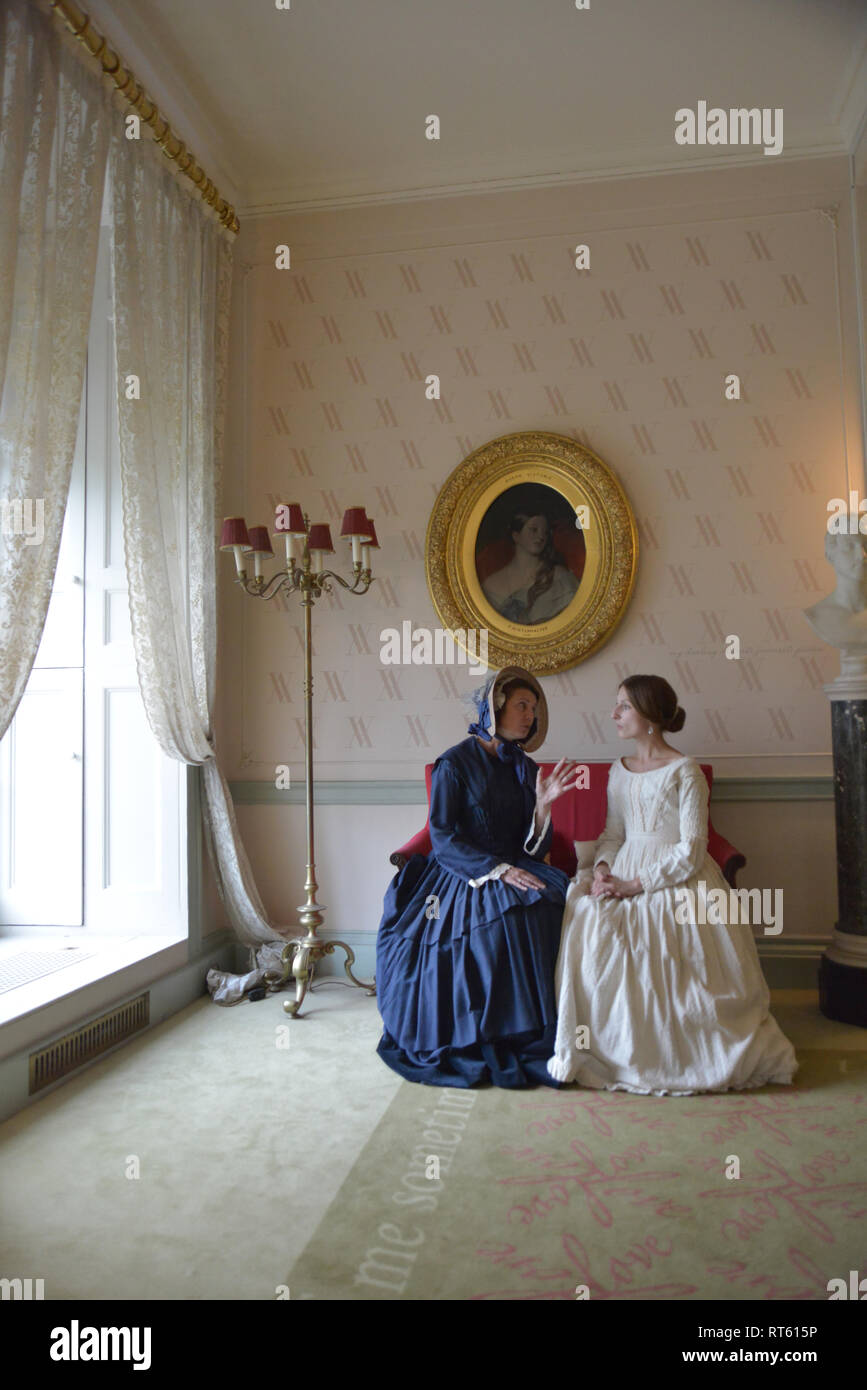 Two Women in Victorian dresses sit and chat in a formal parlour at ...