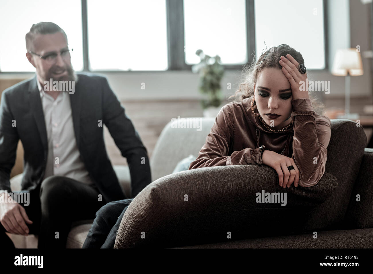 Having no wish. Curly daughter with dark makeup having no wish to talk ...