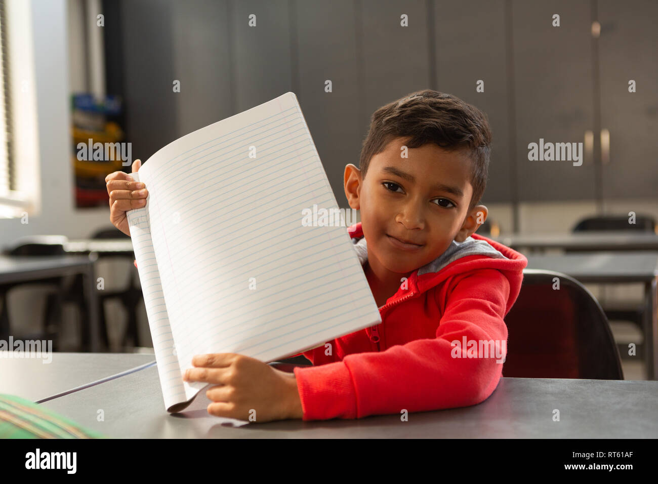 Schoolboy showing notebook in a classroom Stock Photo - Alamy