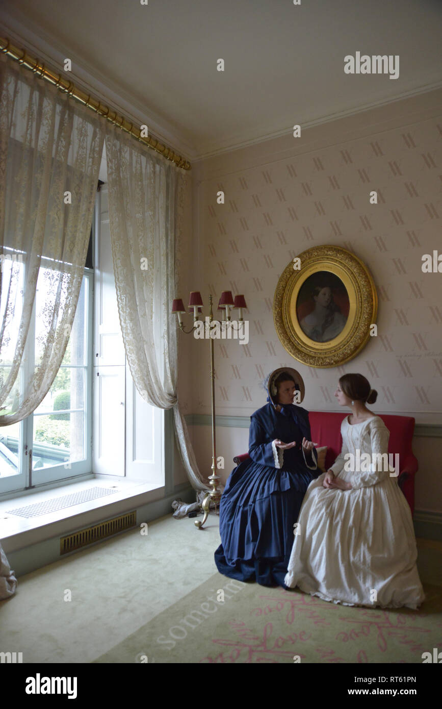 Two Women in Victorian dresses sit and chat in a formal parlour at ...