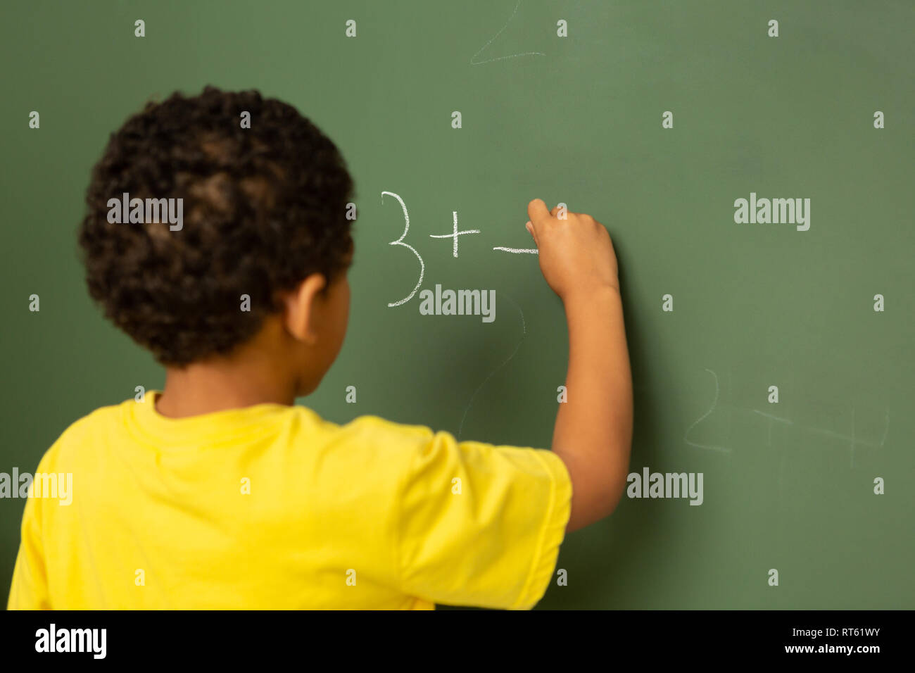 Schoolboy doing math on greenboard in a classroom Stock Photo - Alamy