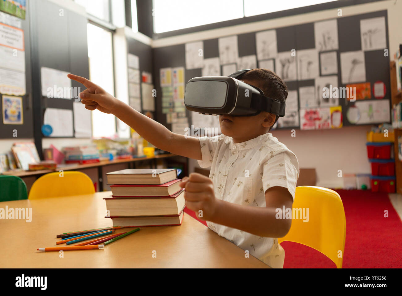 Schoolboy using virtual reality headset at desk in a classroom at ...