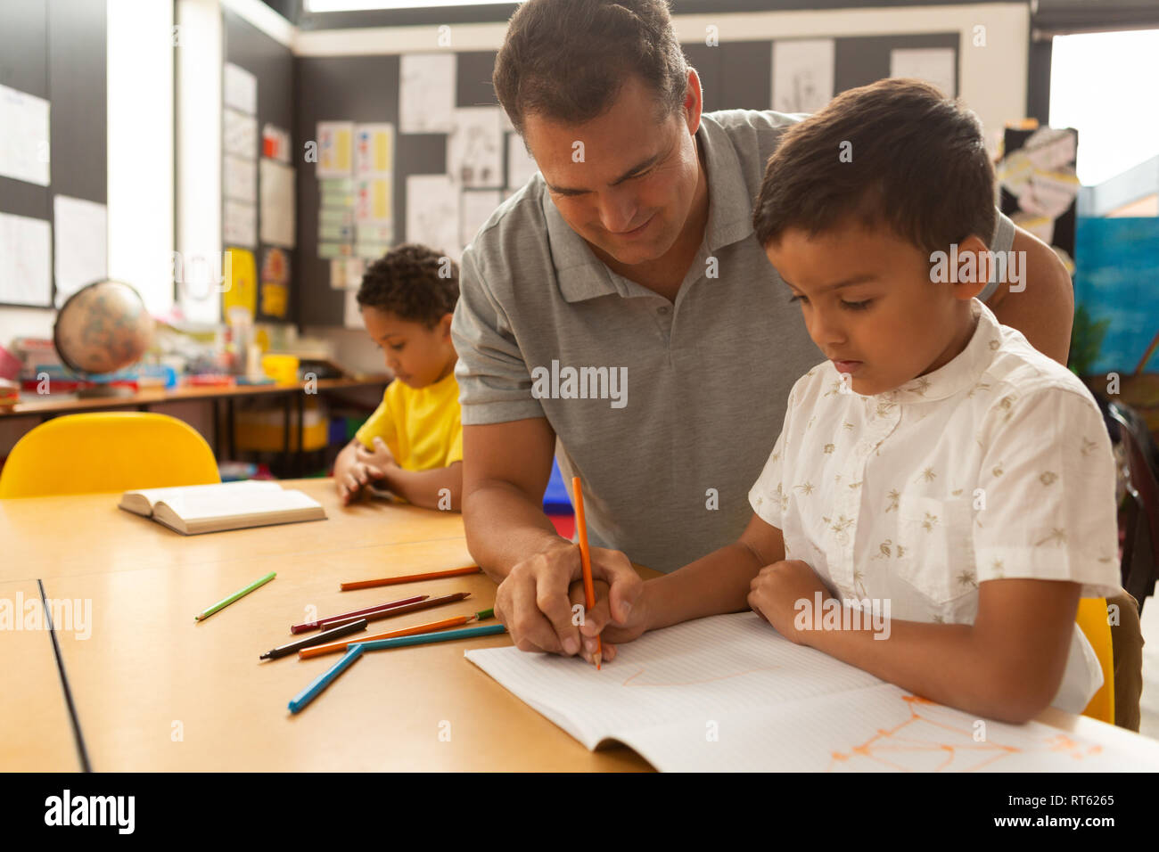 Male teacher teaching a schoolboy in a classroom Stock Photo - Alamy