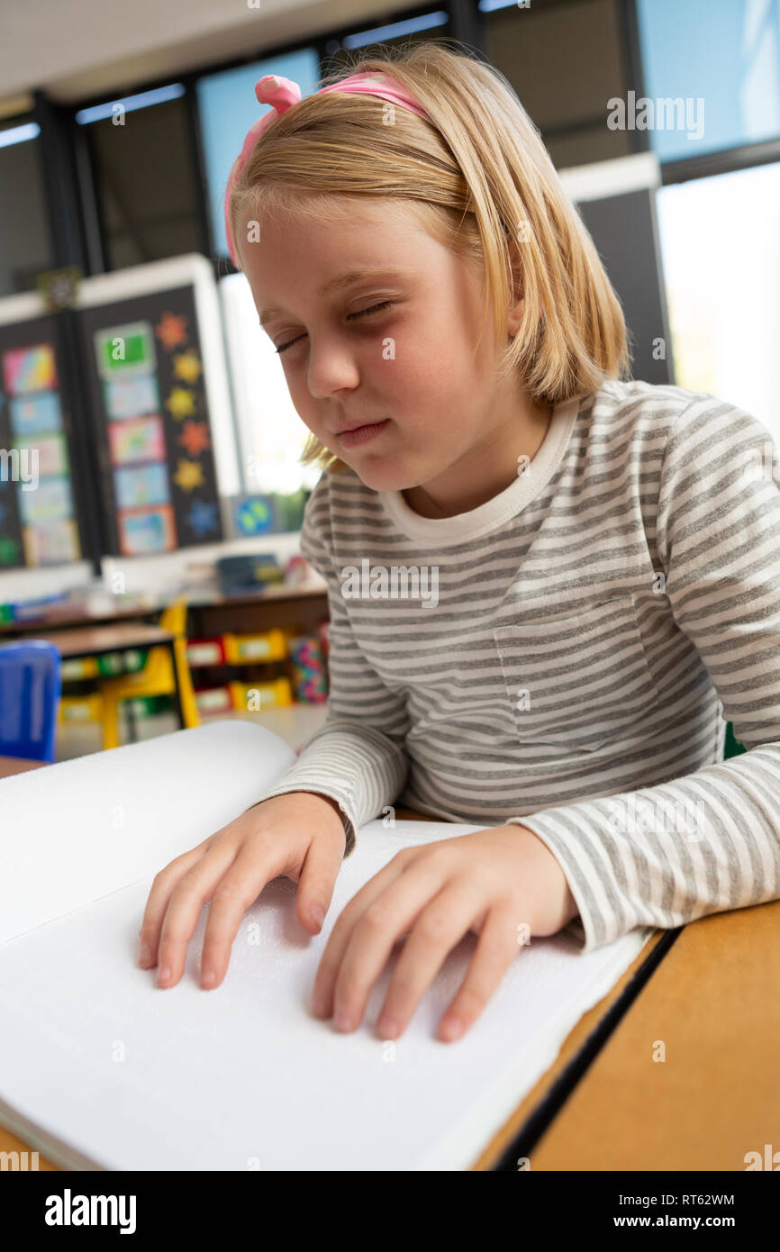 Blind schoolgirl reading a braille book in the classroom Stock Photo ...