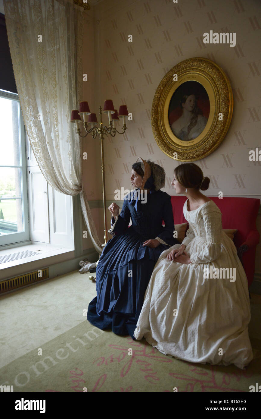 Two Women in Victorian dresses sit and chat in a formal parlour at ...