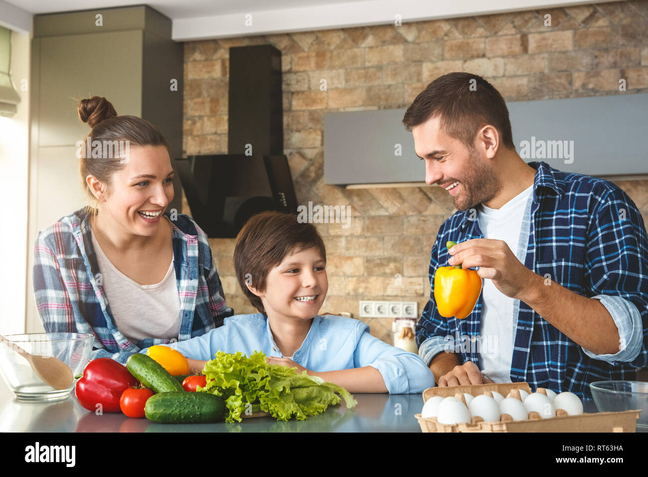 Family at home standing in kitchen together father showing son bell ...