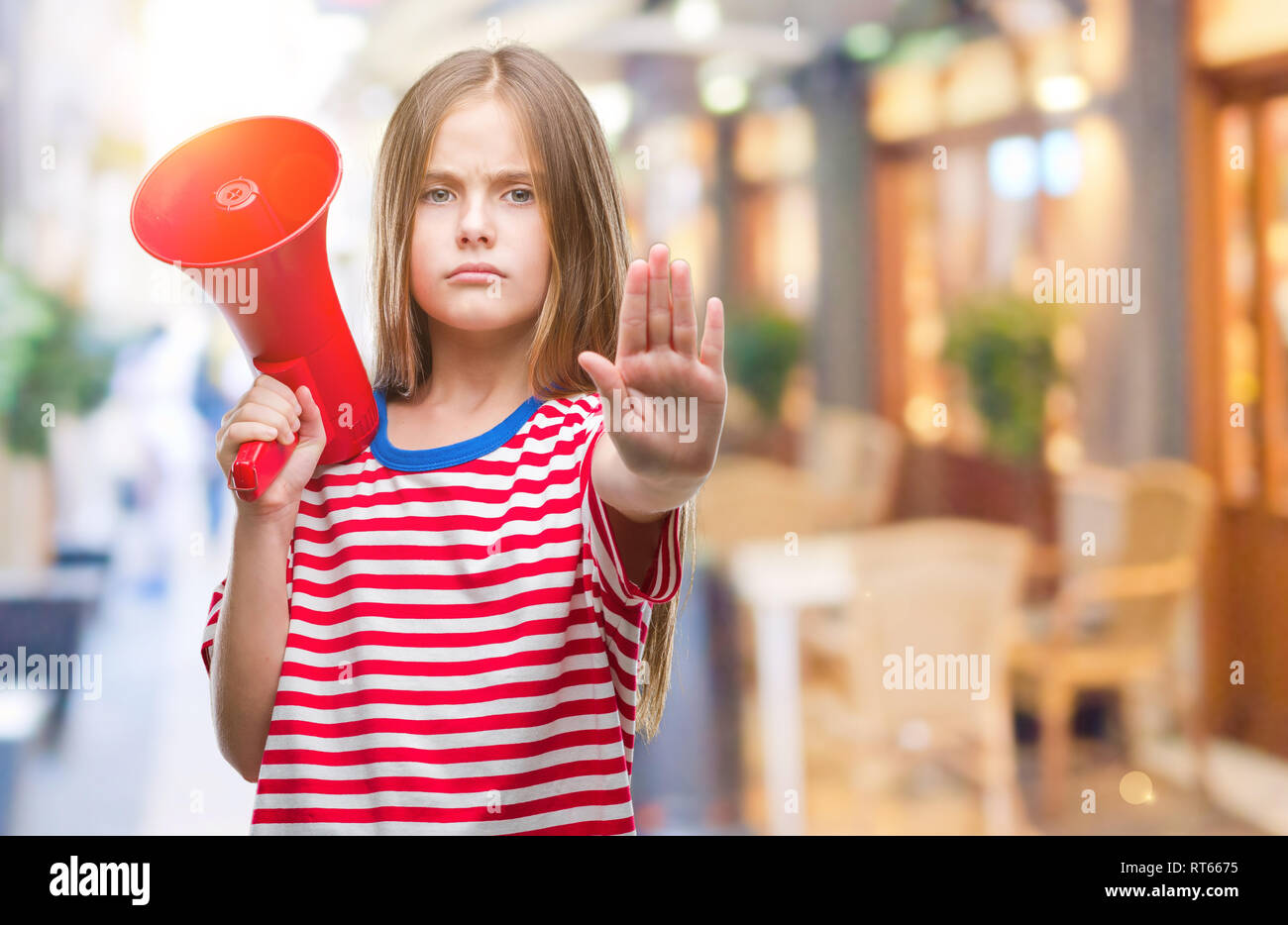 Young beautiful girl yelling through megaphone over isolated background ...