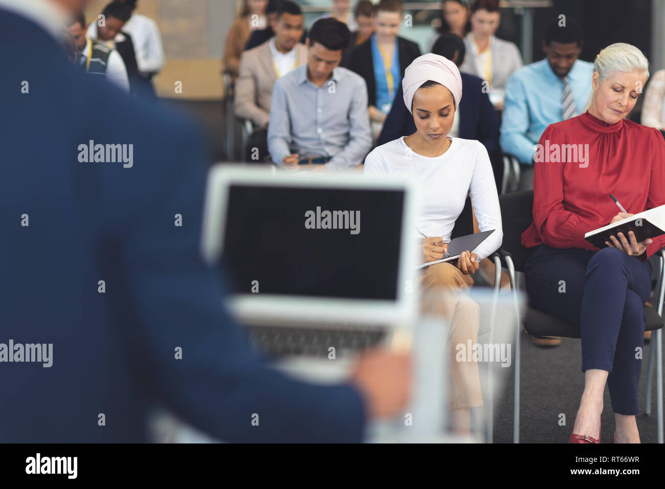 Business people writing notes at a business seminar Stock Photo - Alamy