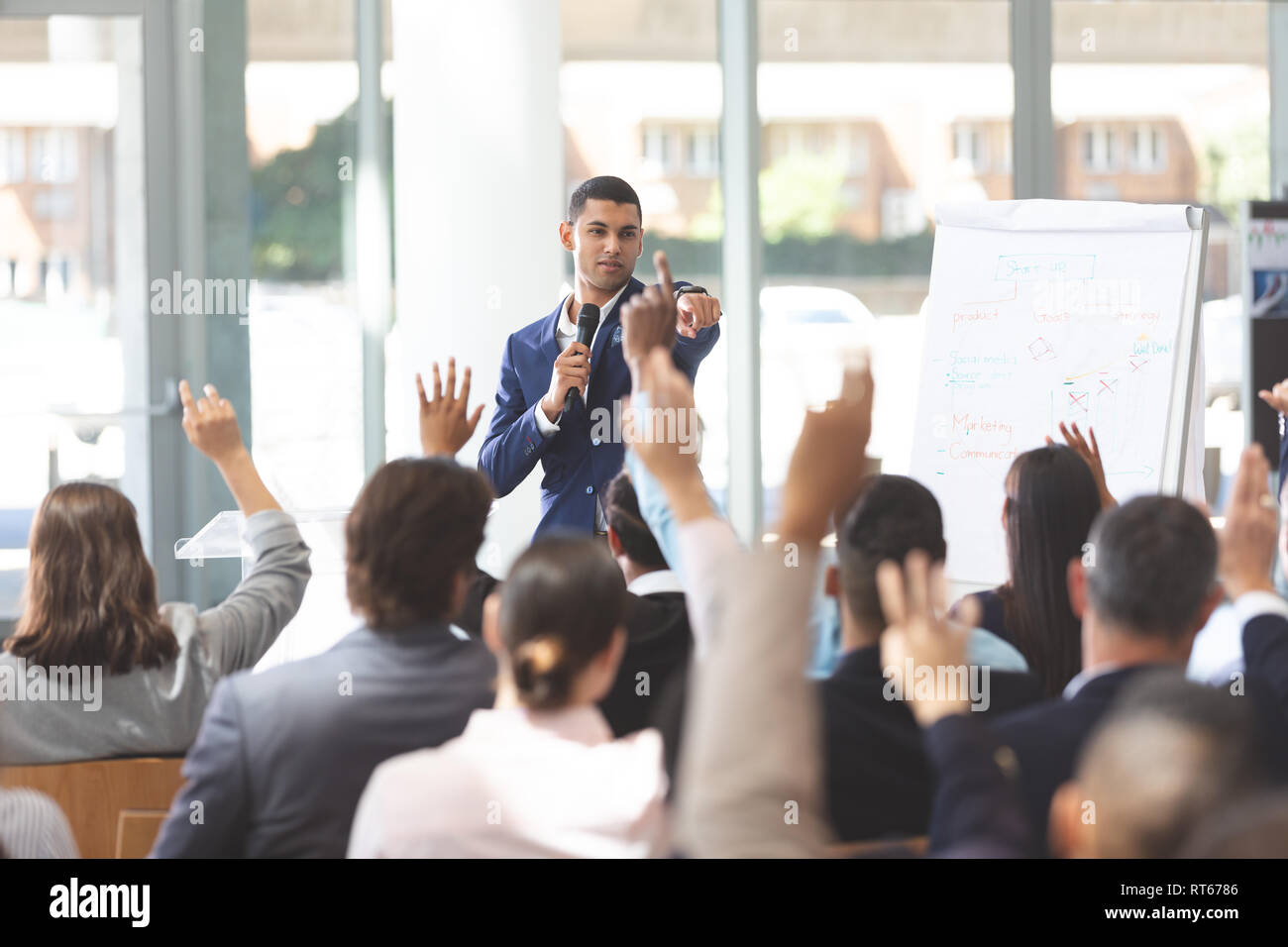 Businessman speaking at business seminar with business people raising ...