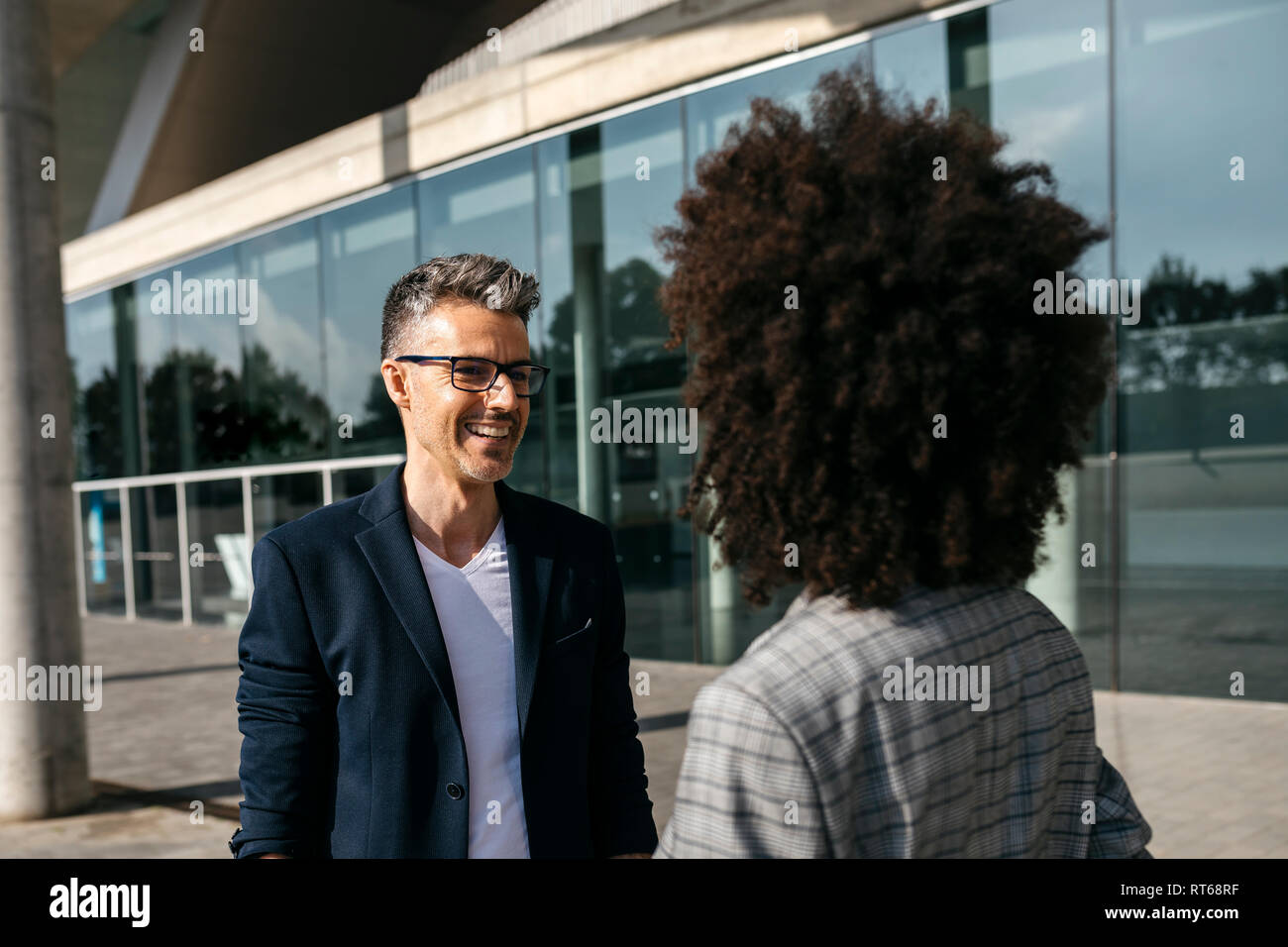 Two colleagues talking outside office building Stock Photo - Alamy