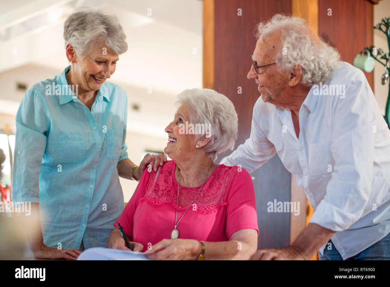 Senior woman signing a contract, friends reassuring her Stock Photo - Alamy