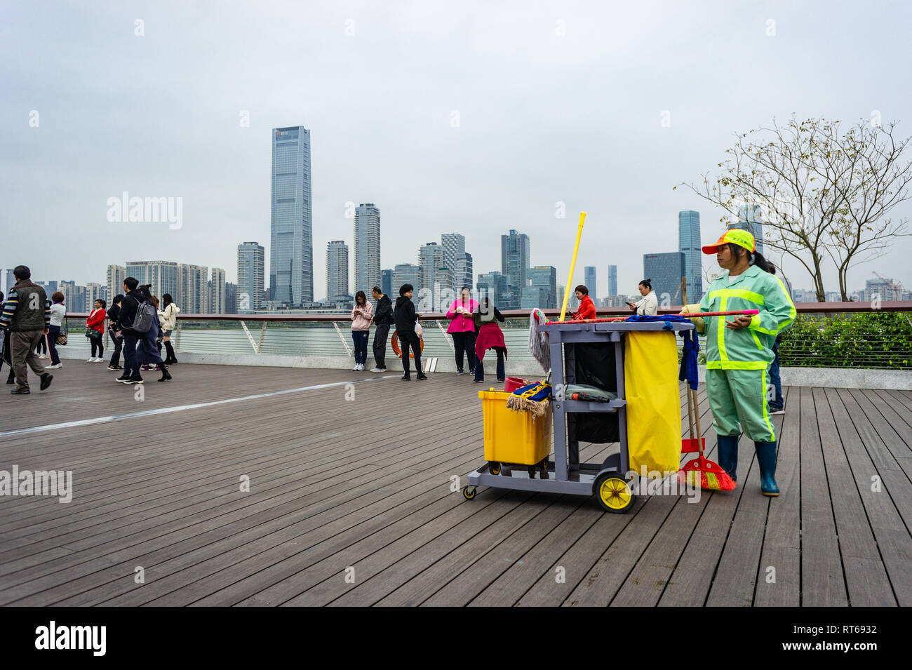 Cleaning lady in uniform in China near her equipment cart in foreground ...