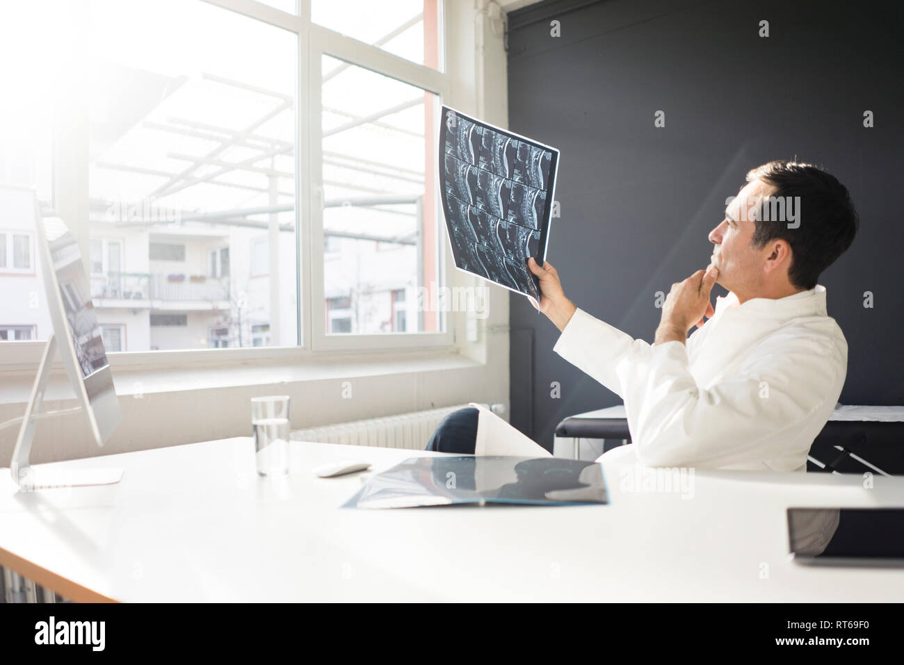 Doctor examining MRT image at desk in medical practice Stock Photo - Alamy