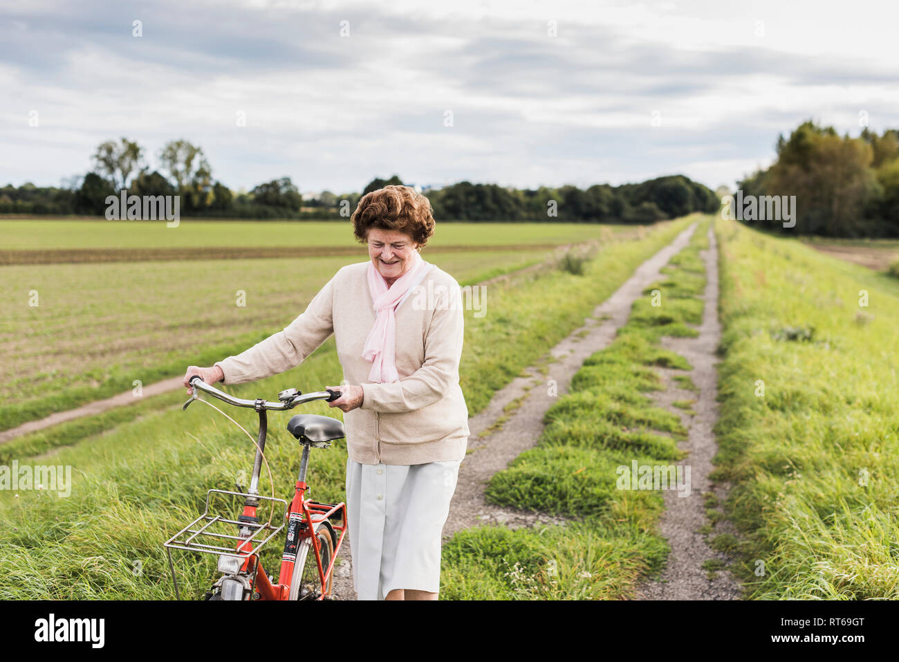 Senior woman pushing bicycle in rural landscape Stock Photo - Alamy