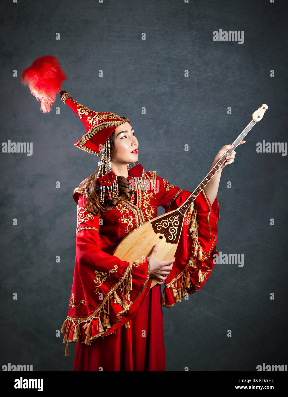 Kazakh woman in red costume playing dombra Kazakh musical instrument at ...