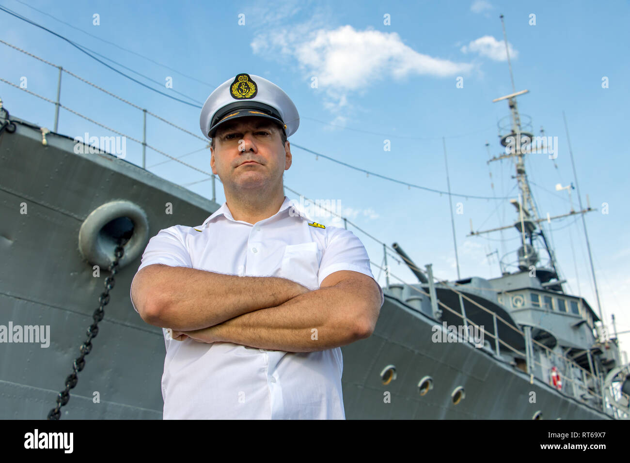 Captain standing in dock before warship and looking ahead. A sailor ...