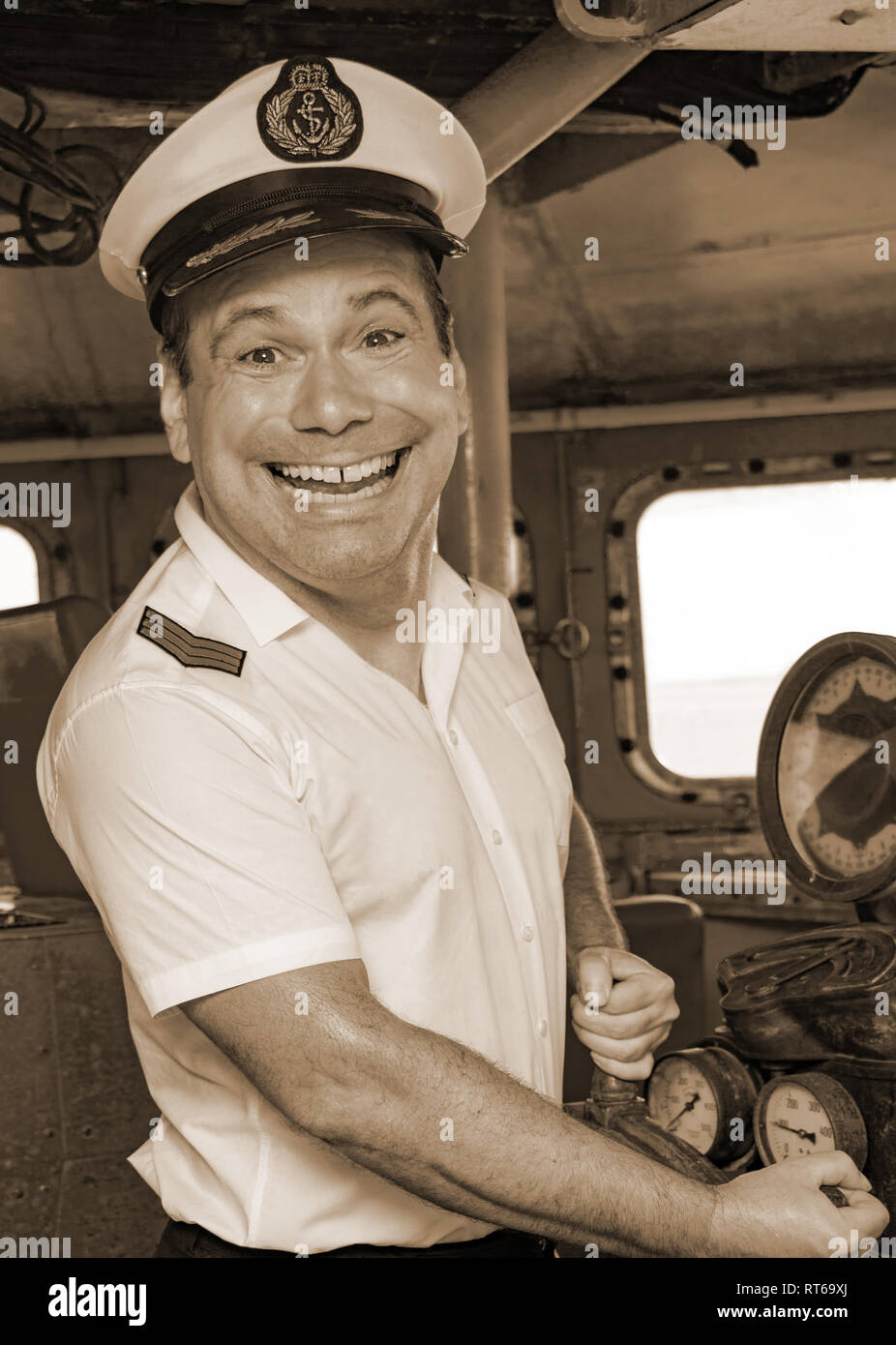 A laughing sailor officer in the uniform is steering the ship with a ...