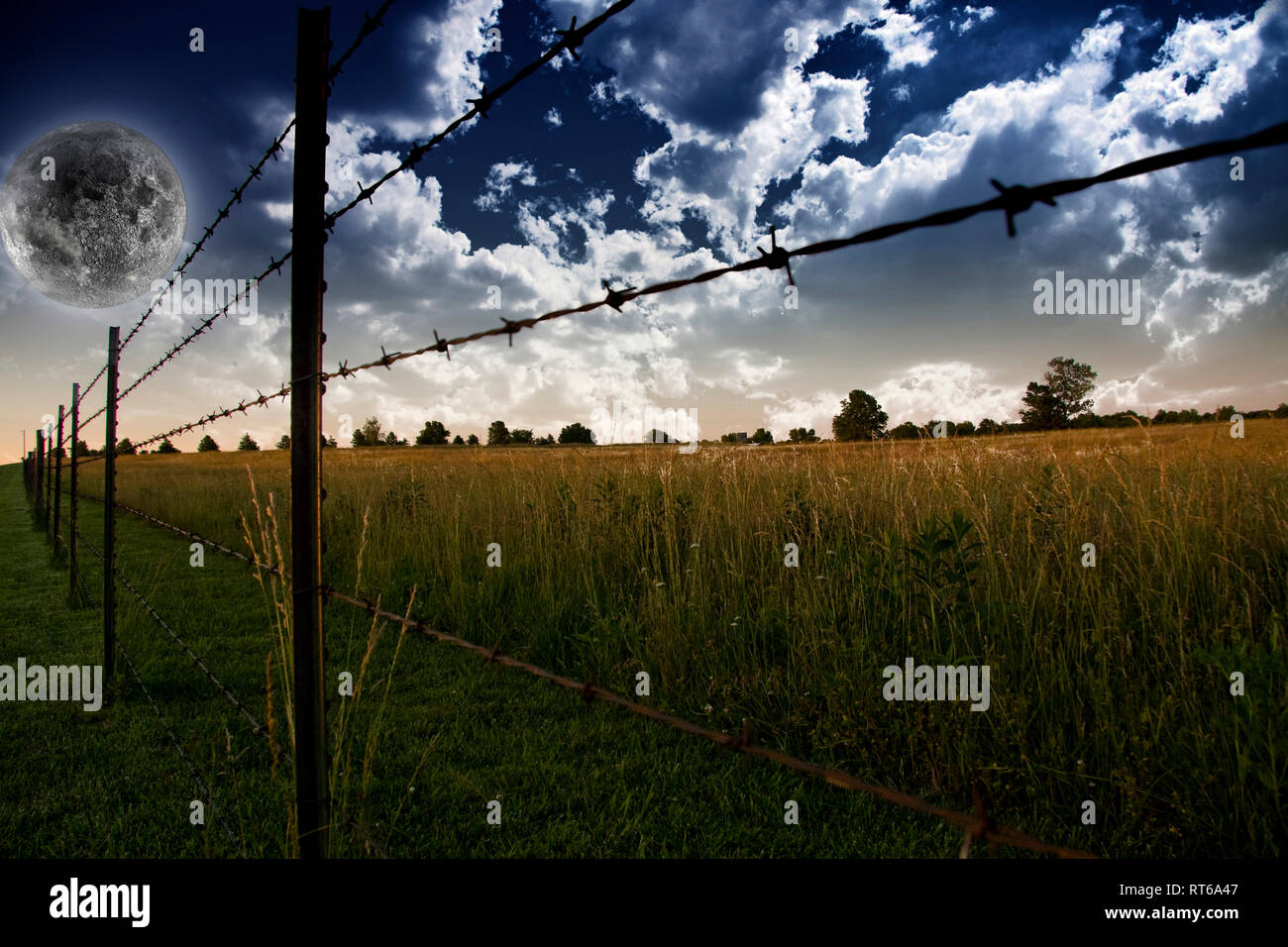 Fence on a farm field with giant full moon in a cloudy sky Stock Photo ...