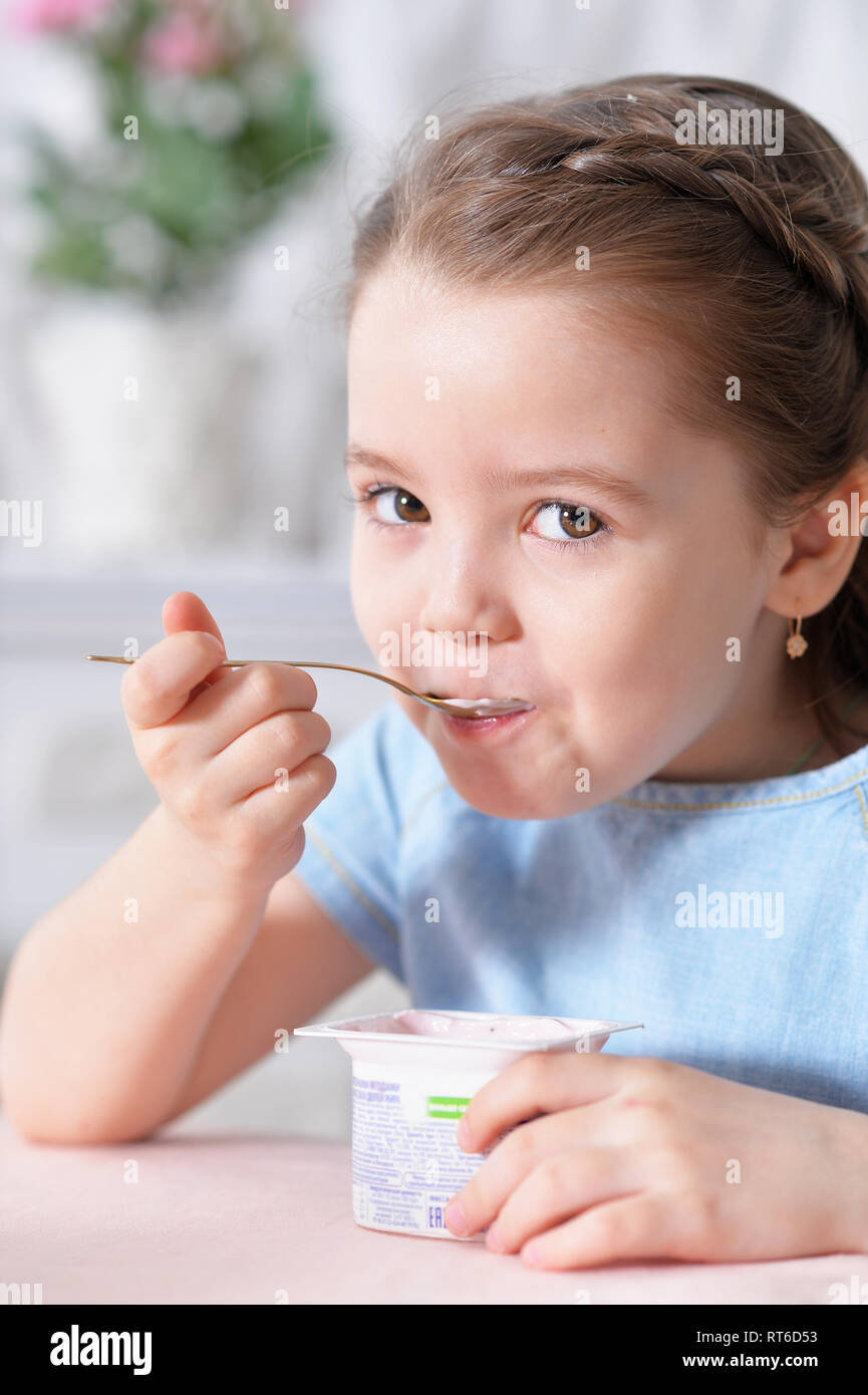 Portrait of cute little girl eating delicious yogurt Stock Photo - Alamy