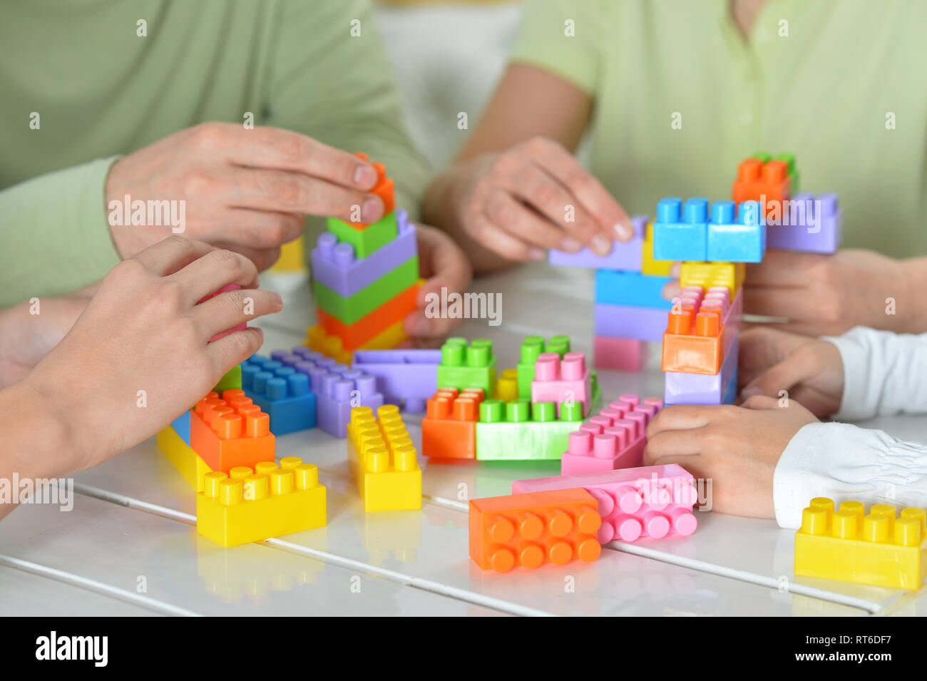 Parents and children playing with colorful plastic blocks Stock Photo ...