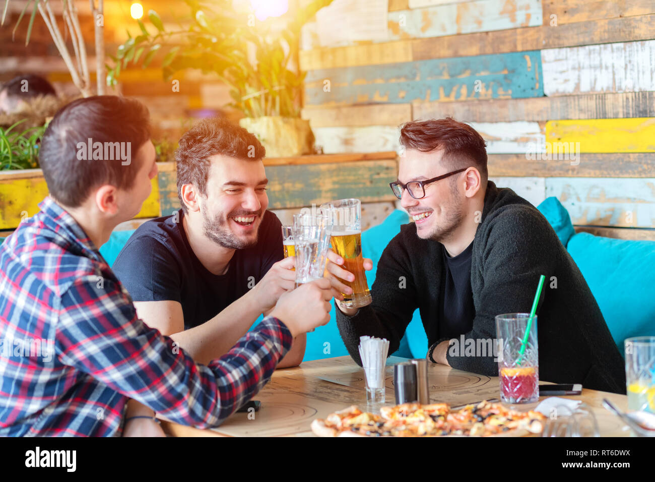 Three young men enjoy drinking beer at trendy pub Stock Photo - Alamy