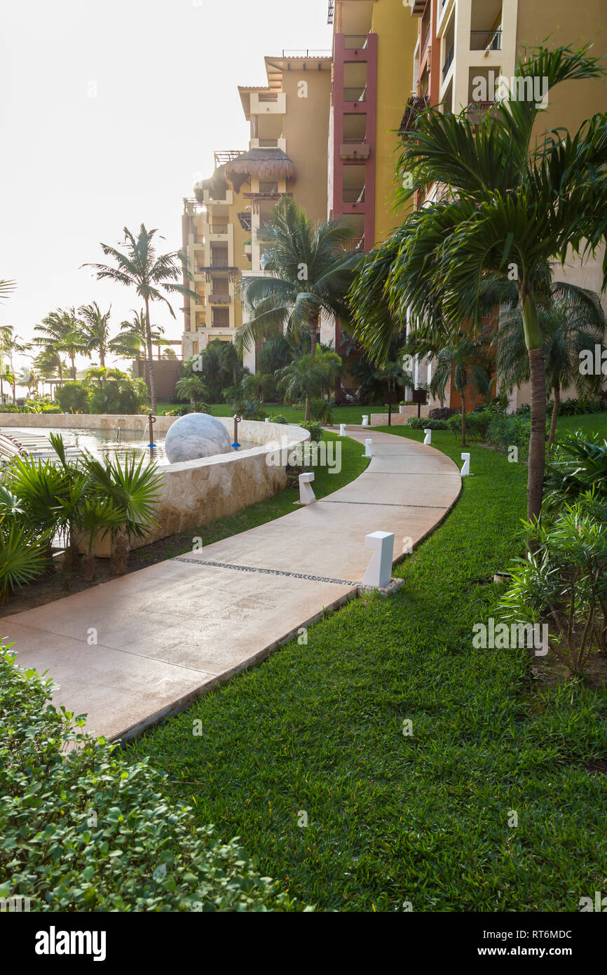 A walking path with garden and palm trees at a high end Mexican resort ...