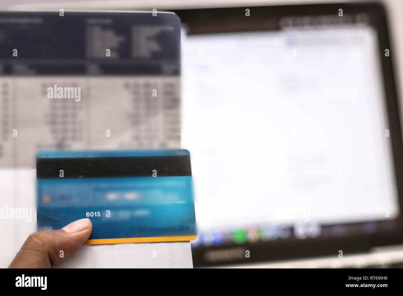 hand holding credit card and bank account with monitor showing e ...