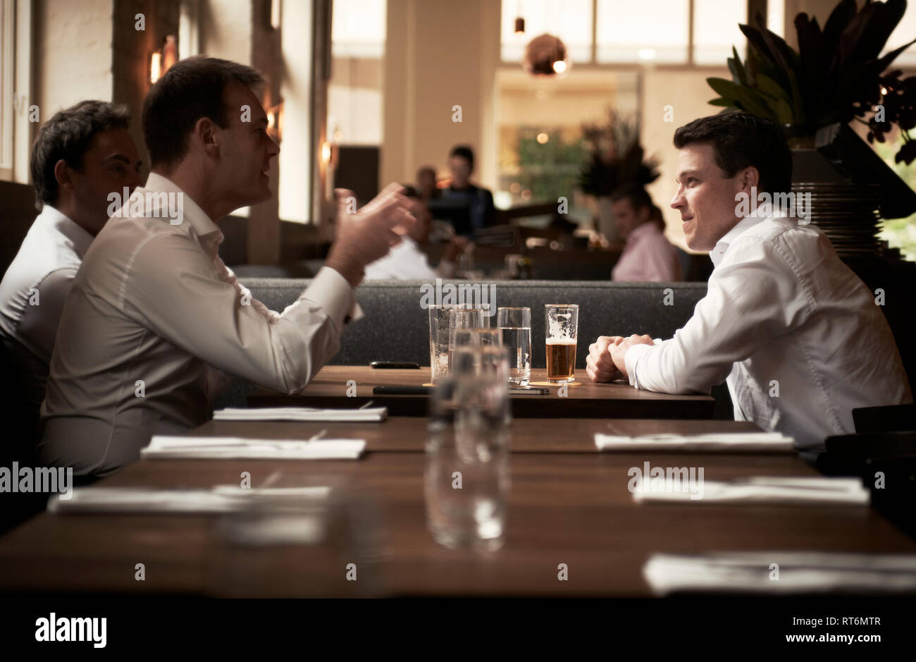 Several male patrons in a busy bar enjoy an alcoholic beverage at lunch ...
