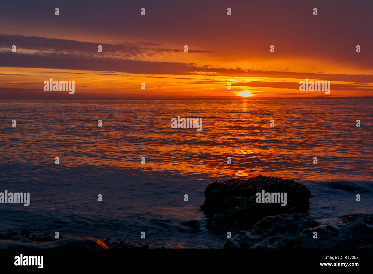 The setting sun reflecting onto the sea Stock Photo - Alamy