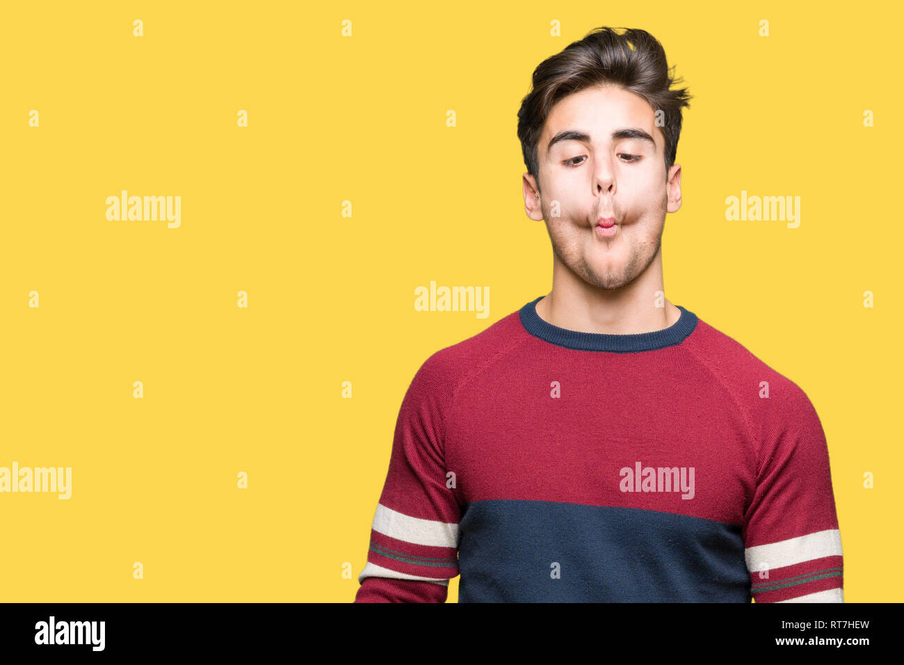 Young handsome man over isolated background making fish face with lips ...