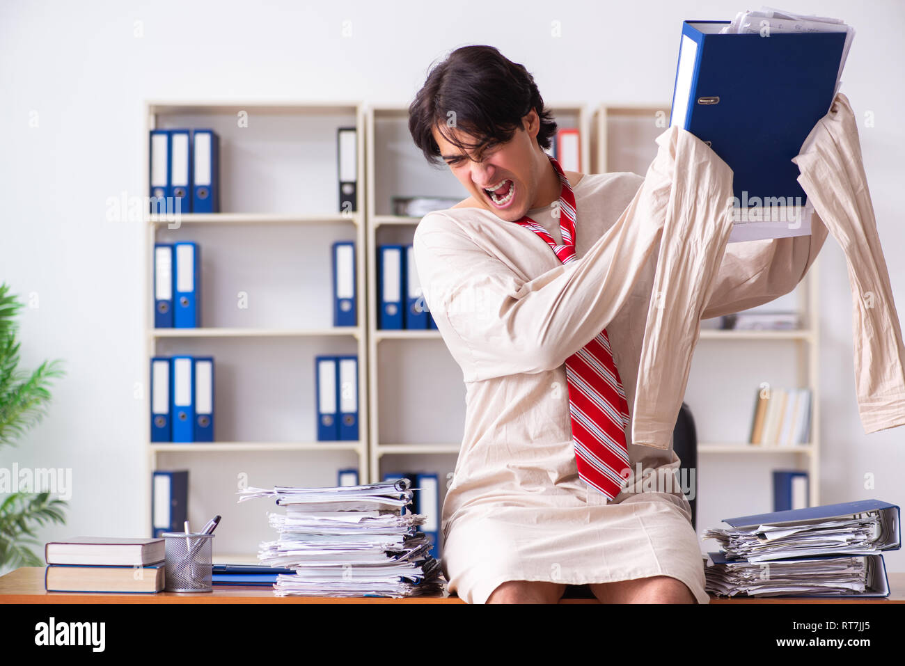 Crazy young man in straitjacket at the office Stock Photo - Alamy