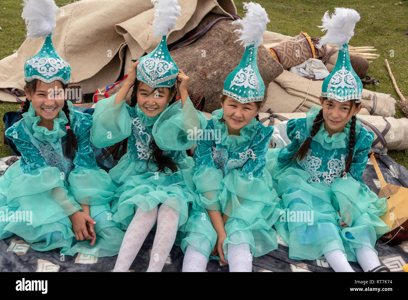 Smiling Kazakh girls in festive attire sitting on yurt constructing ...