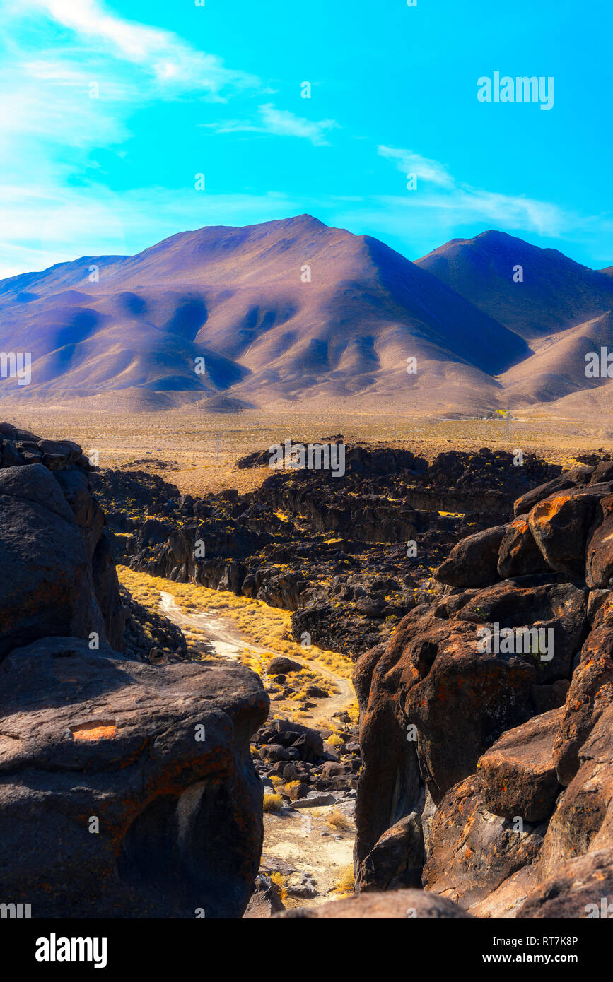 Looking down through rocky canyon to barren desert valley and mountains ...