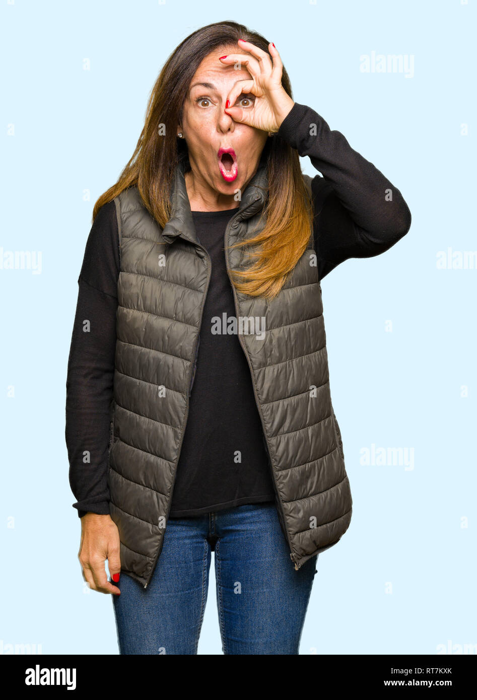 Beautiful middle age woman wearing winter vest doing ok gesture shocked ...