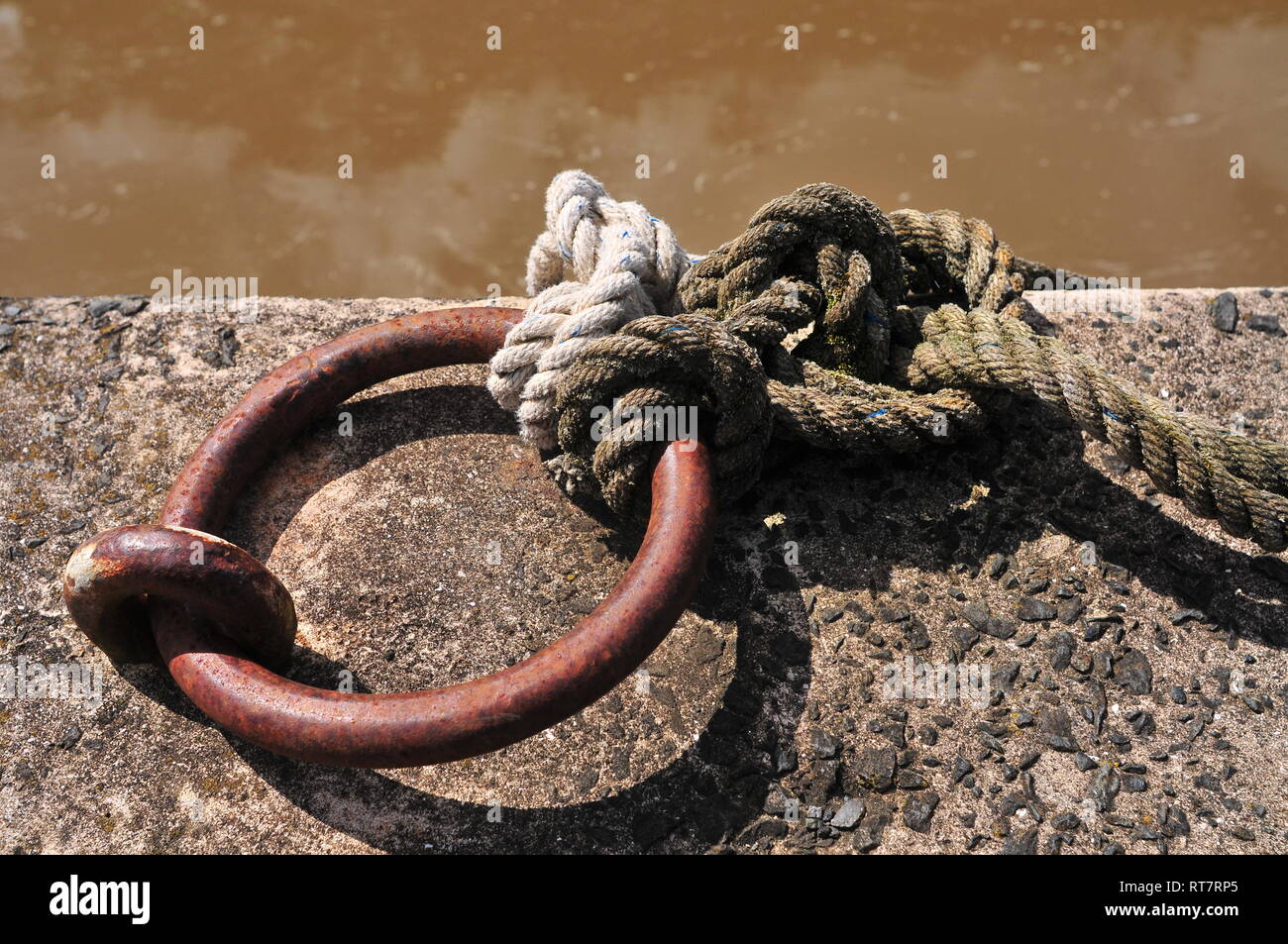 Thick rope tied to large thick rusty steel ring attached to concrete jetty Stock Photo - Alamy