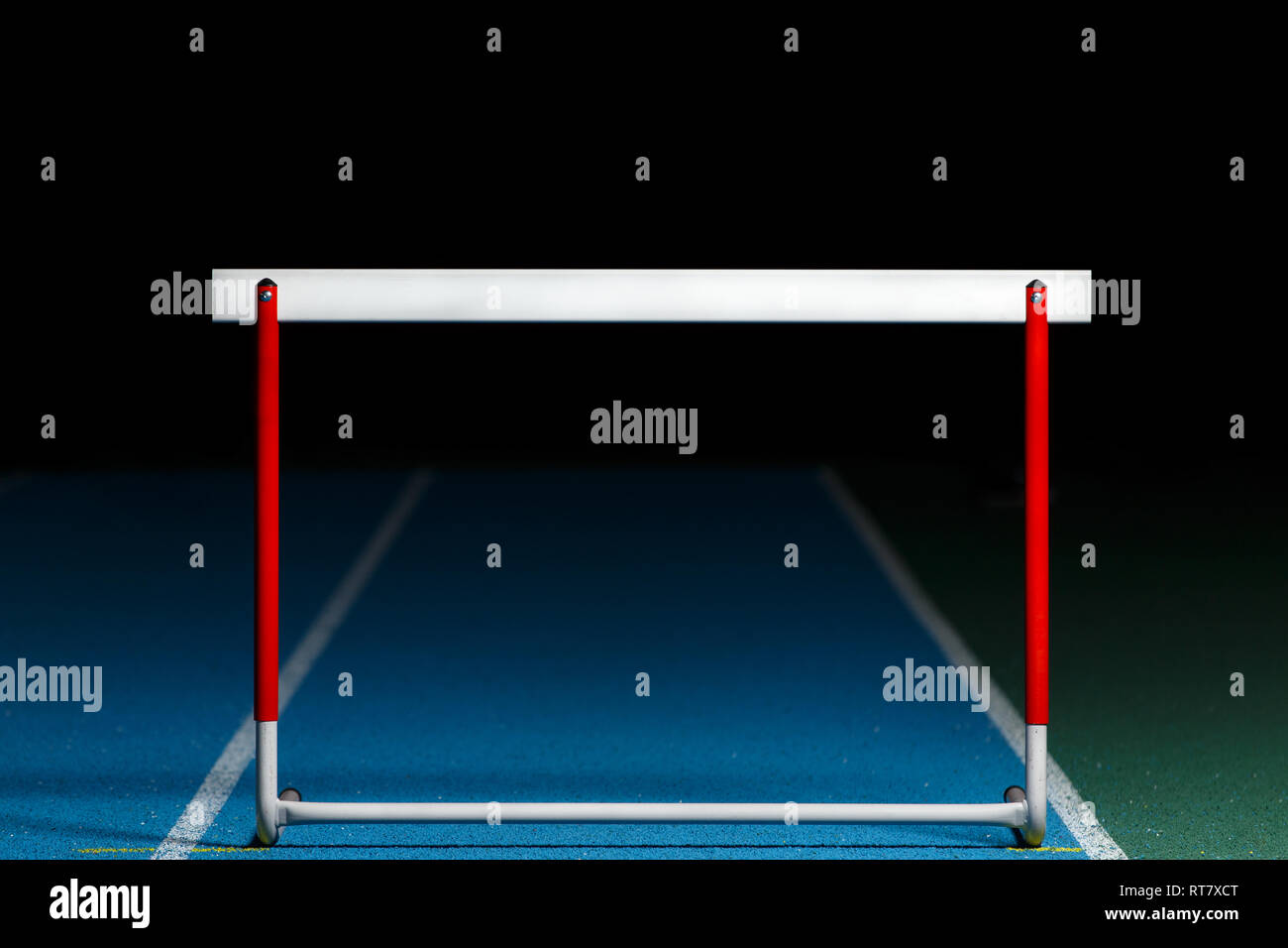One hurdle on the sprint lane against black background. Athletics ...