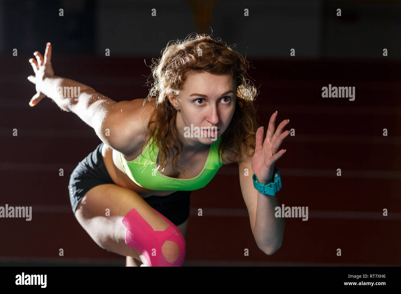 Female athlete starting sprint race running from blocks against black ...