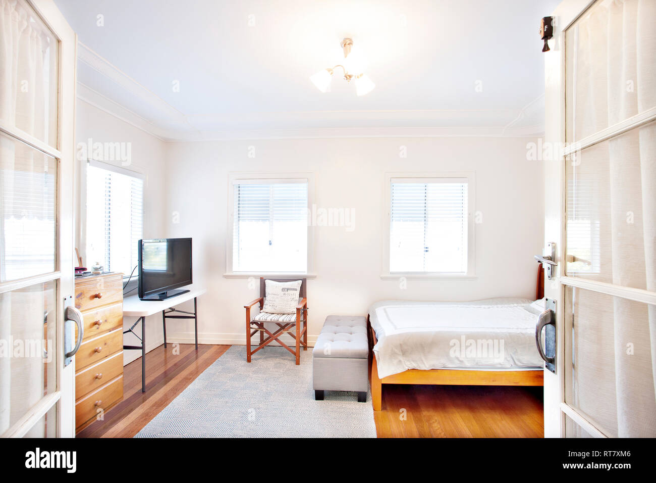Neat white bedroom with wooden furniture and a divan style bed viewed ...