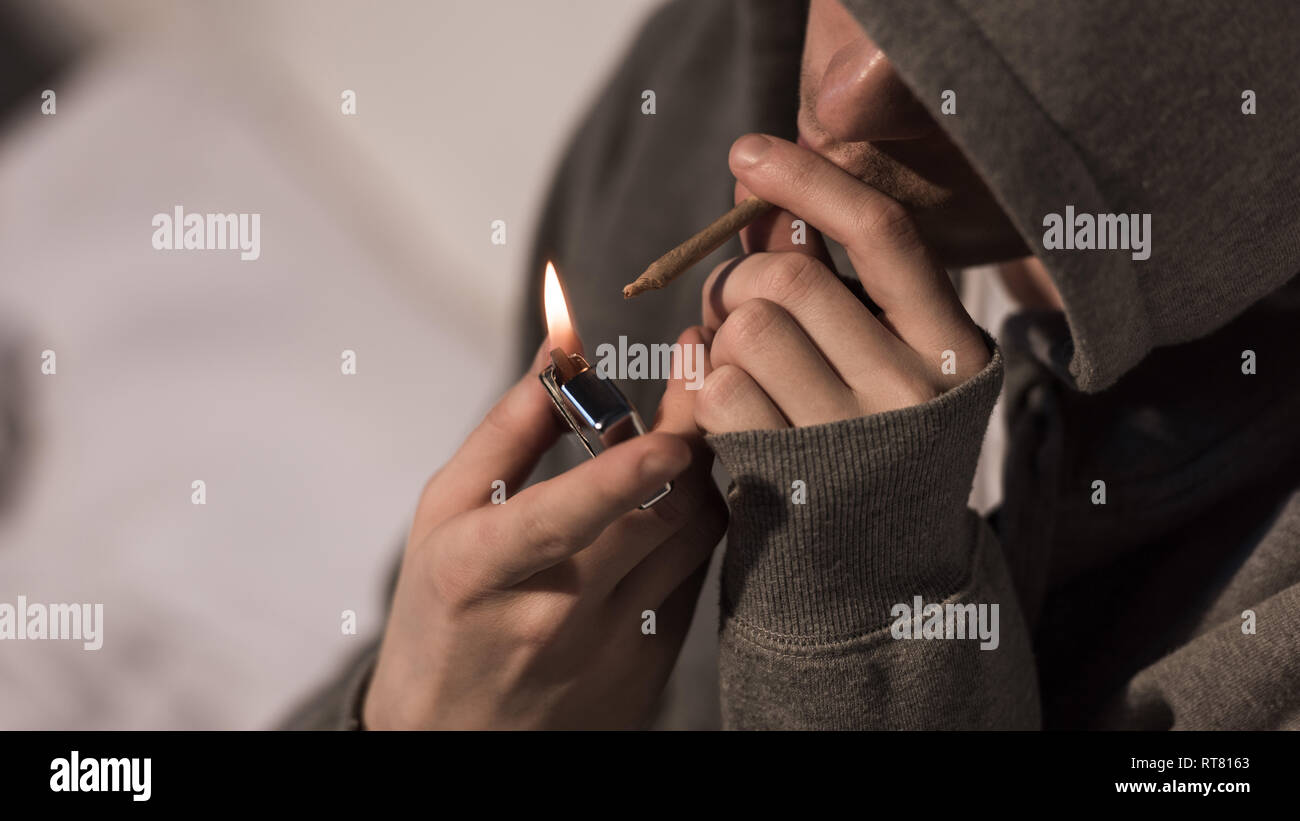 selective focus of junkie man lightening rolled marijuana cigarette ...
