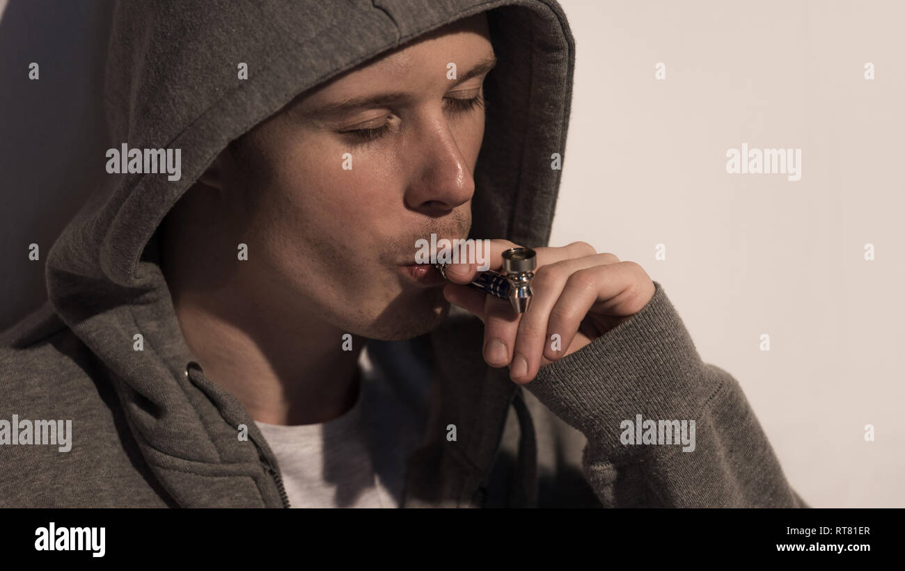 junkie man in hood smoking pipe with closed eyes Stock Photo - Alamy