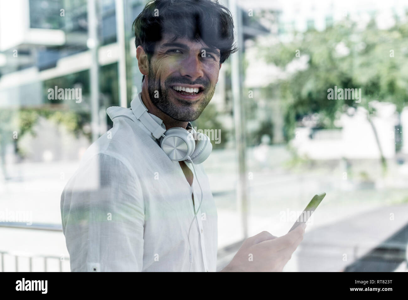Portrait of smiling young man holding cell phone in the city Stock ...