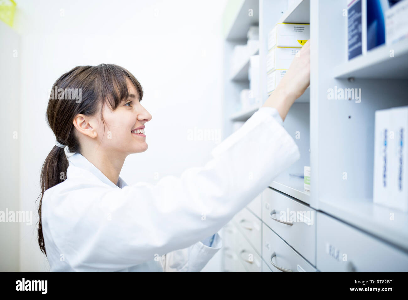 Smiling pharmacist checking medicine at cabinet in pharmacy Stock Photo ...