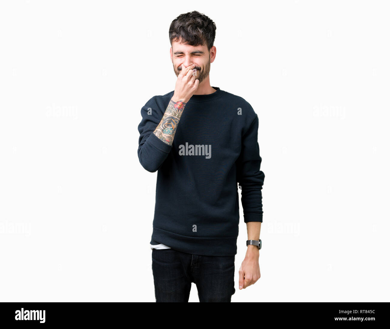 Young handsome man over isolated background smelling something stinky ...