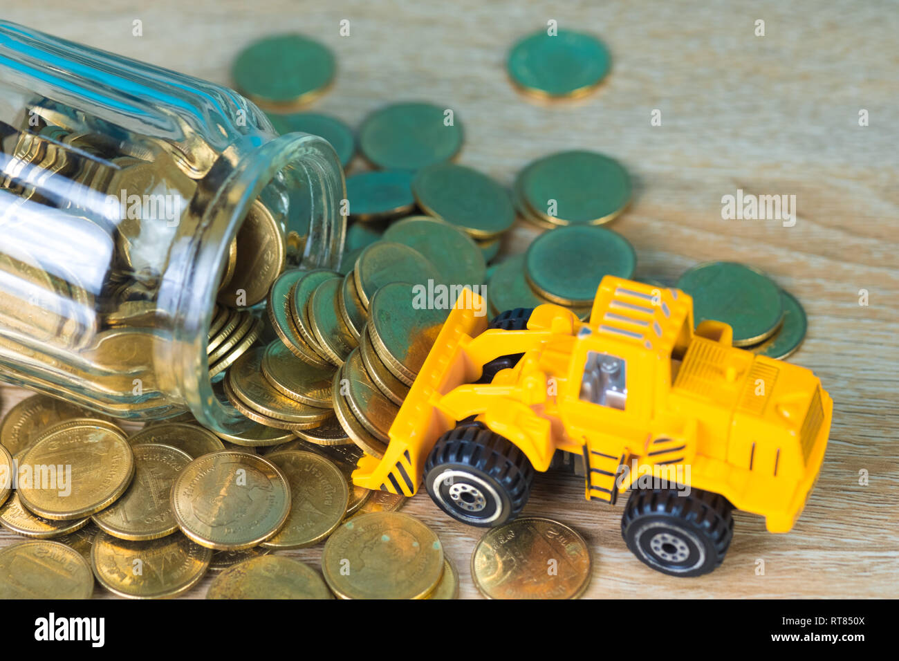 Mini bulldozer truck loading stack coin with pile of gold coin to glass ...