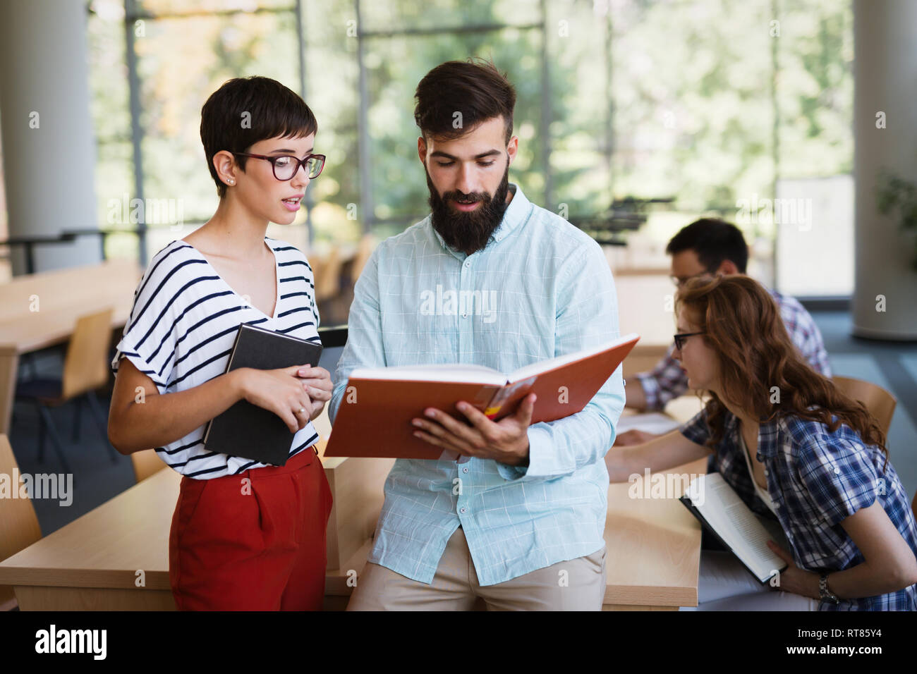 Young happy students sitting in library Stock Photo - Alamy