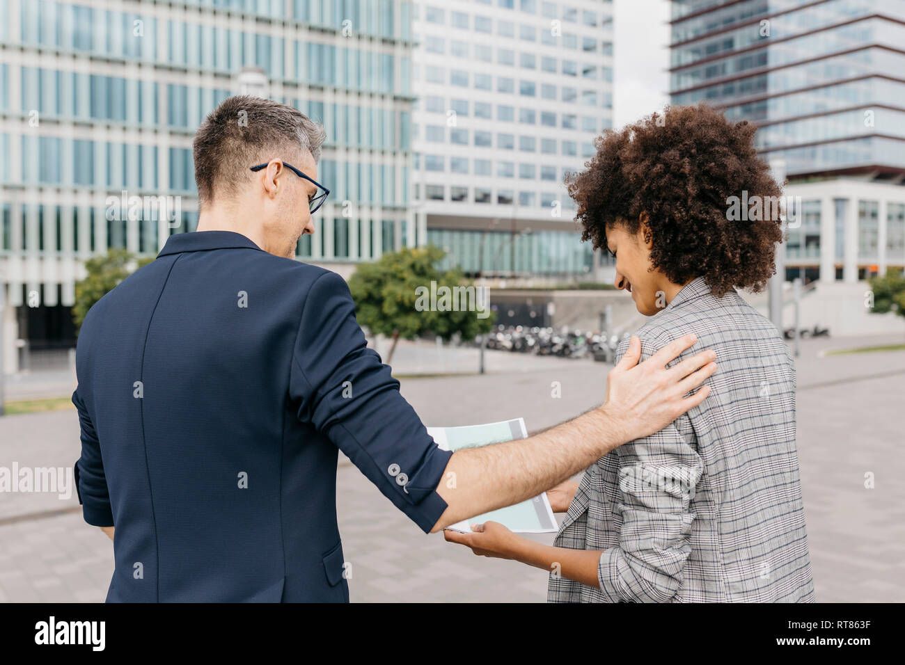 Two colleagues looking at paper outside office building Stock Photo - Alamy