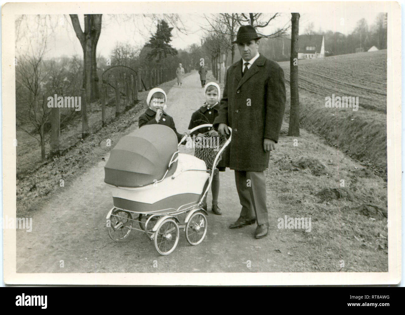 Germany.1963s . Father walking with his twin daughters and with the ...