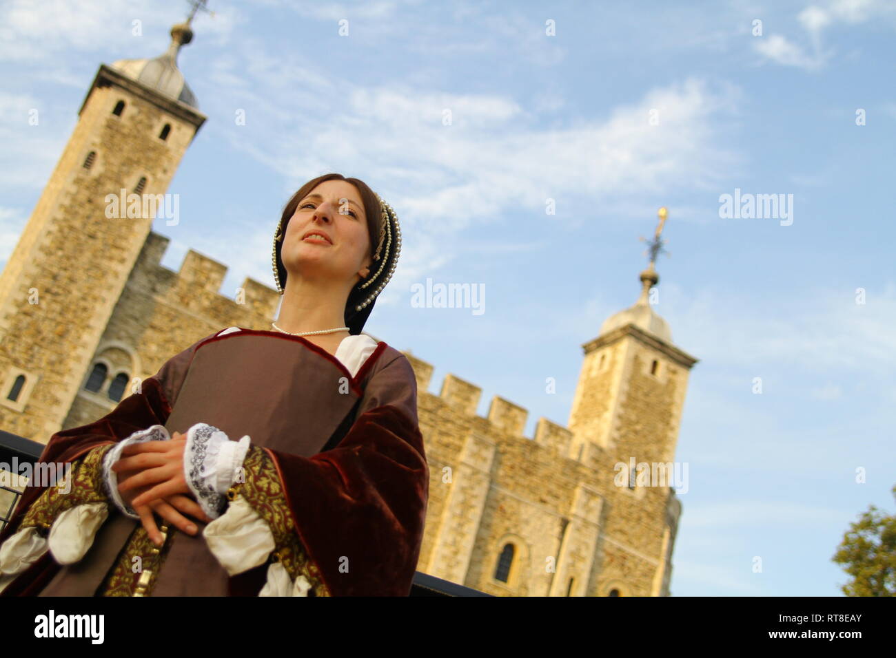 A beautiful young Woman dressed as Anne Boleyn sits by a window at the ...
